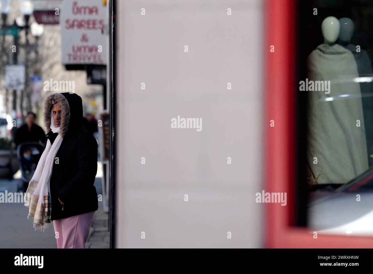 A pedestrian bundles up as he waits for a bus at a bus stop in Chicago ...