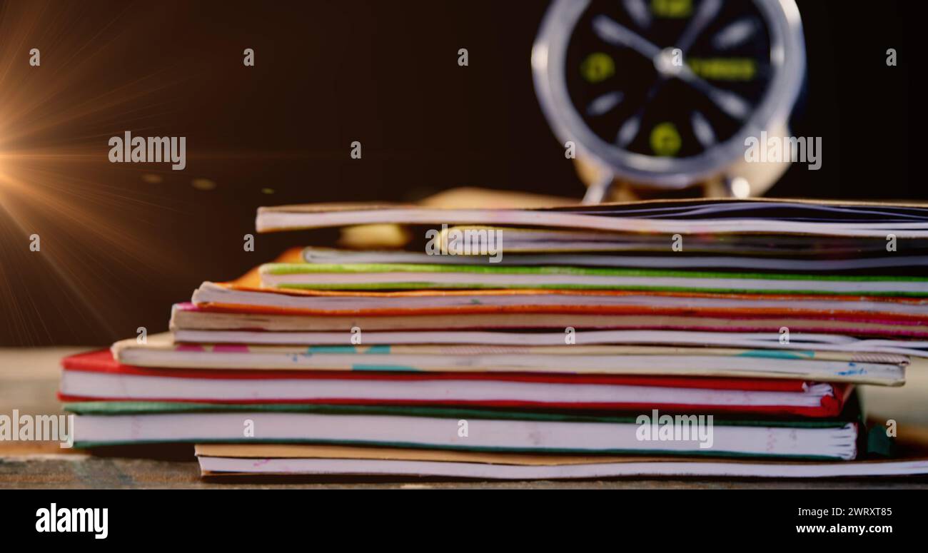 Image of glowing light over alarm clock on stack of books Stock Photo ...
