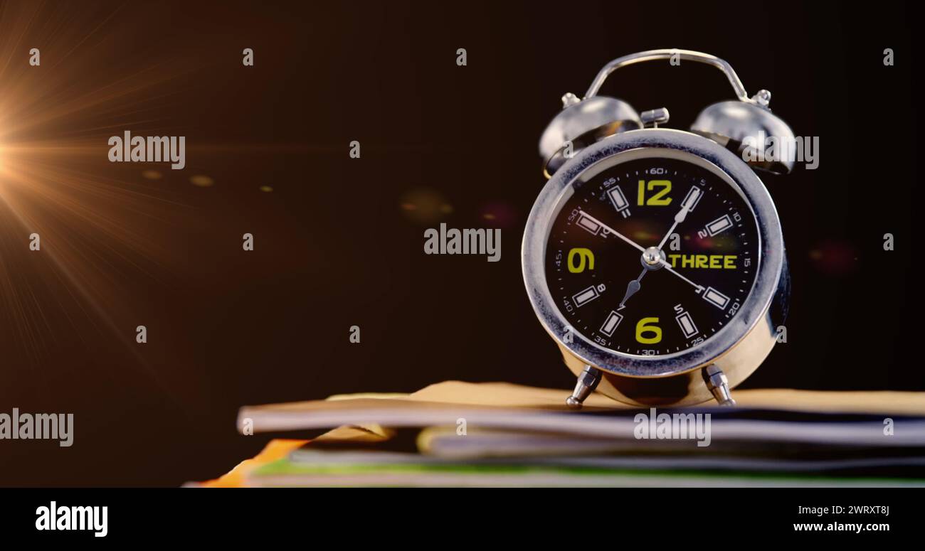 Image of glowing light over alarm clock on stack of books ...