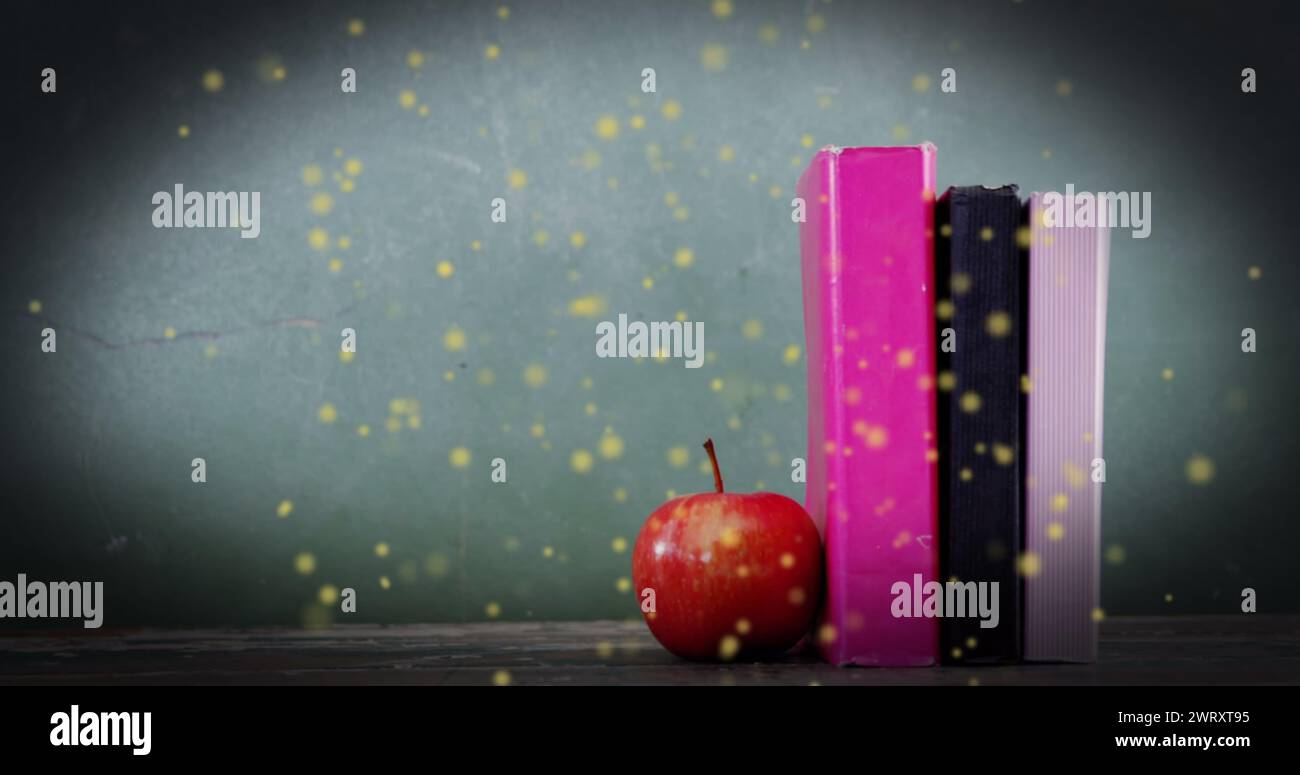 Image of glowing spots over apple and books on green background ...