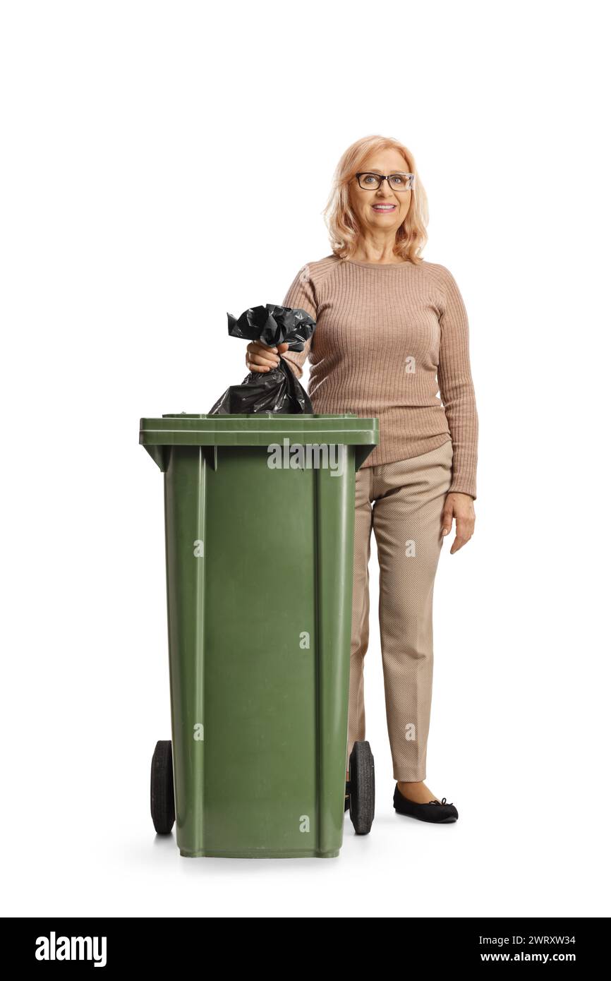 Full length portrait of a middle aged woman throwing a waste bag in a ...