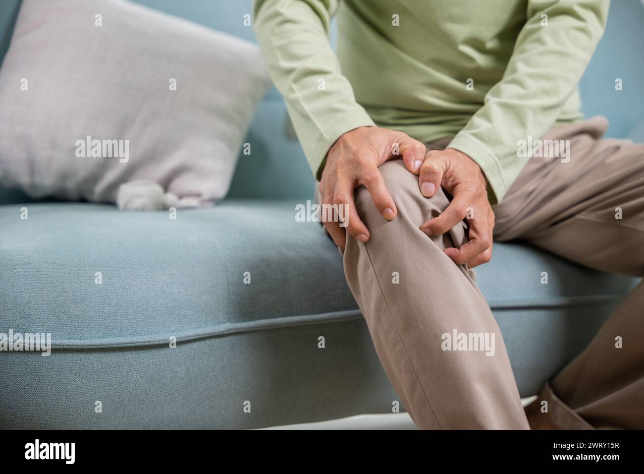 Asian senior man retirement knee joint pain on sofa Stock Photo - Alamy