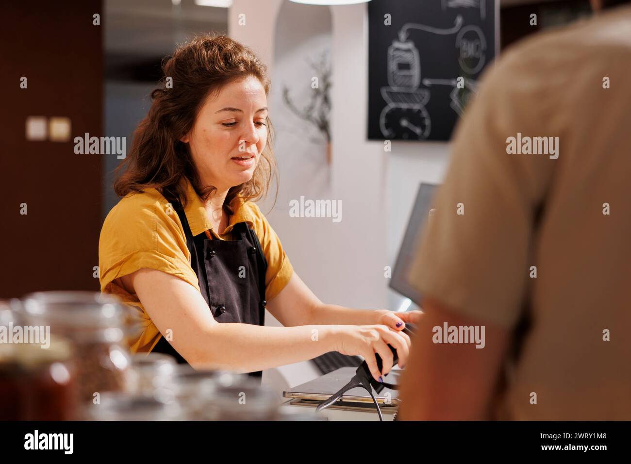 Vendor at zero waste supermarket checkout counter using bar code ...