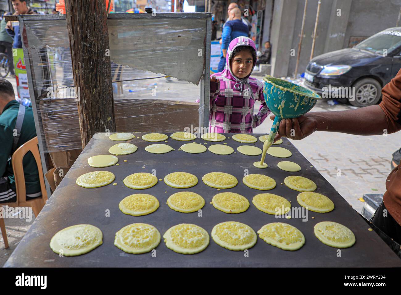 Gaza. 14th Mar, 2024. A child stands by a stall making traditional ...