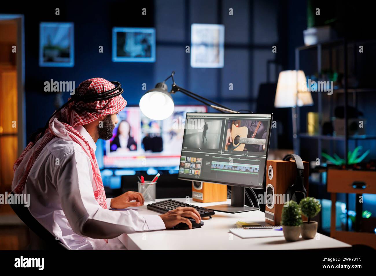 A Middle Eastern man edits video information on his computer screen ...