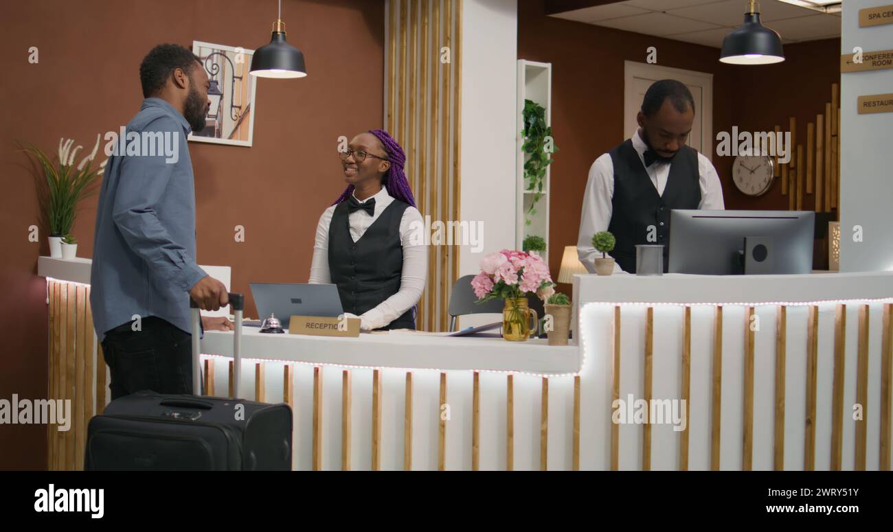 Tourist arriving with suitcase at hotel front desk, receiving room ...