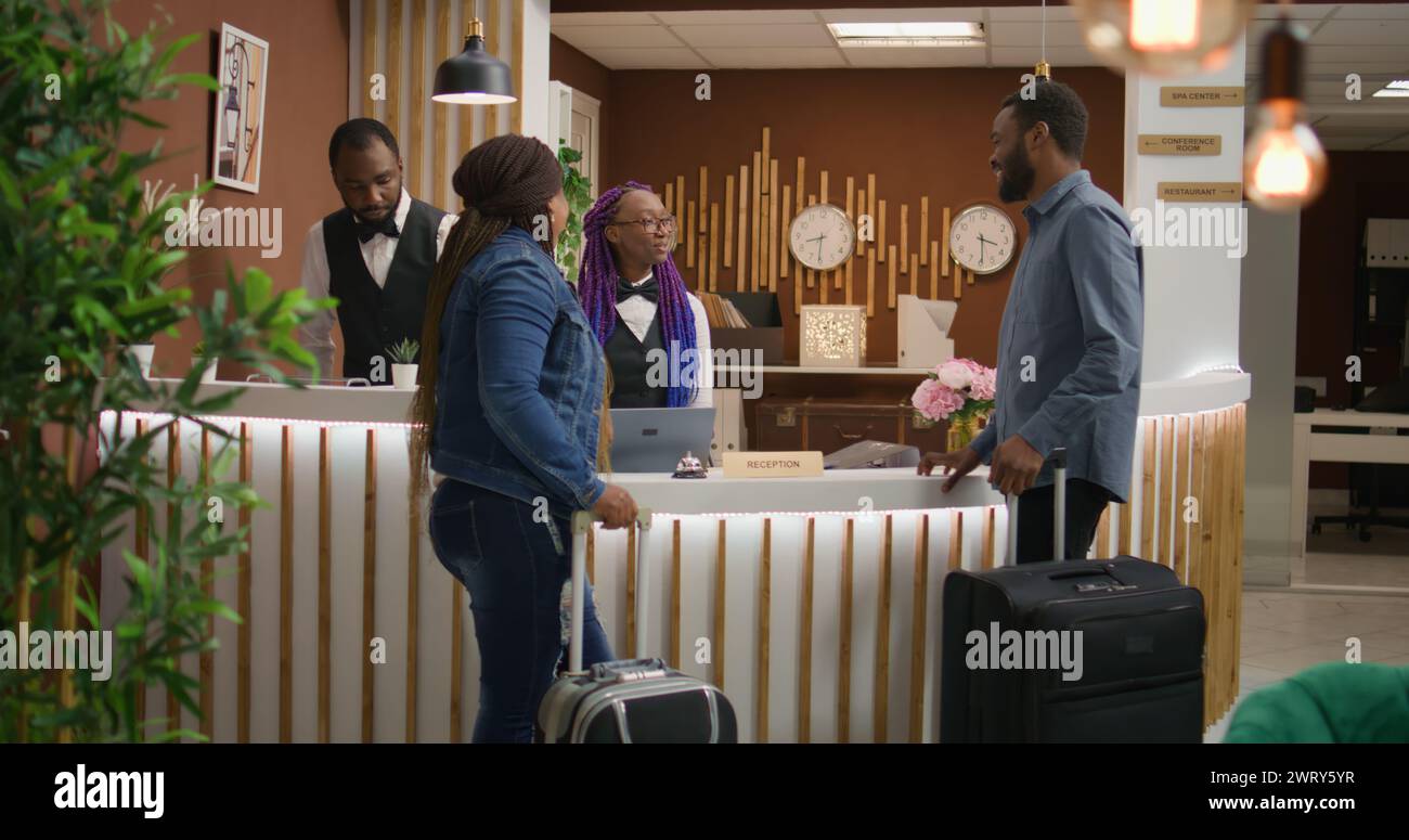 Receptionist greeting tourists at hotel, asking for personal ...