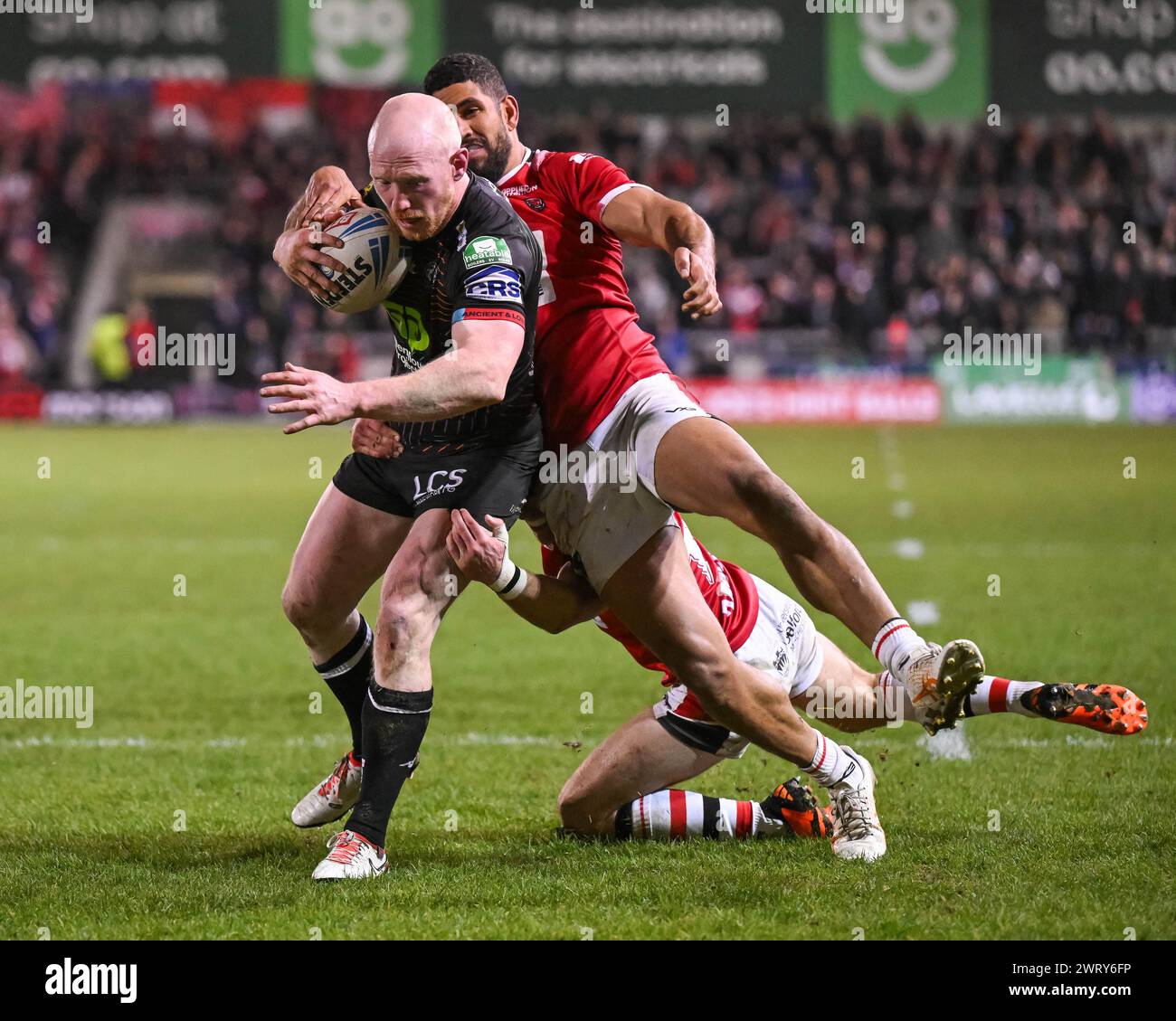 Liam Farrell of Wigan Warriors is tackled by Nene Macdonald of Salford Red Devils during the ...