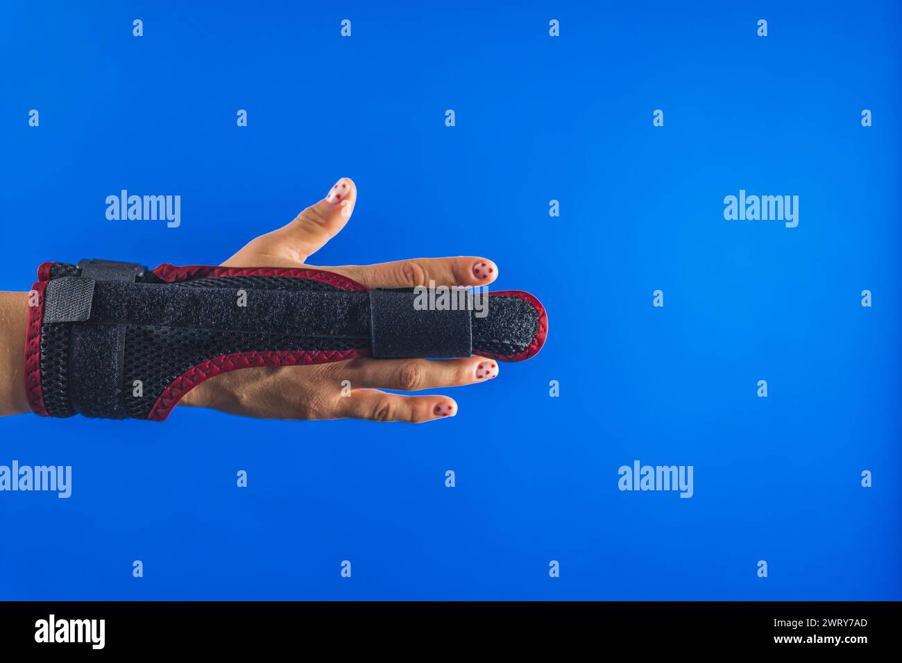 hand with a splint on a middle finger over a blue background. High ...