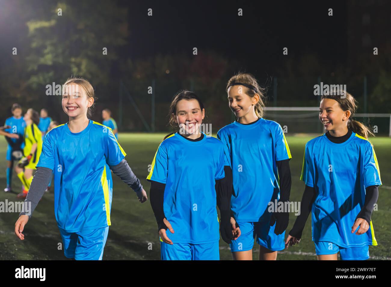 cheerful little girls in football uniforms having a break during soccer ...