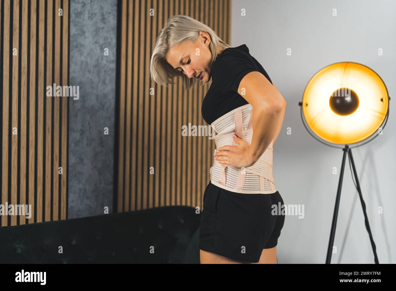 Woman in back pain from spinal injury wearing lumbar brace corset at ...