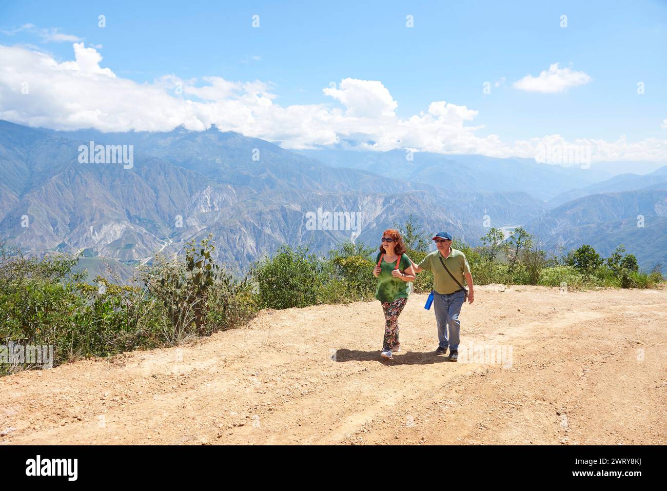 Latin senior hiking couple walking relaxed along a rural Andean road up ...