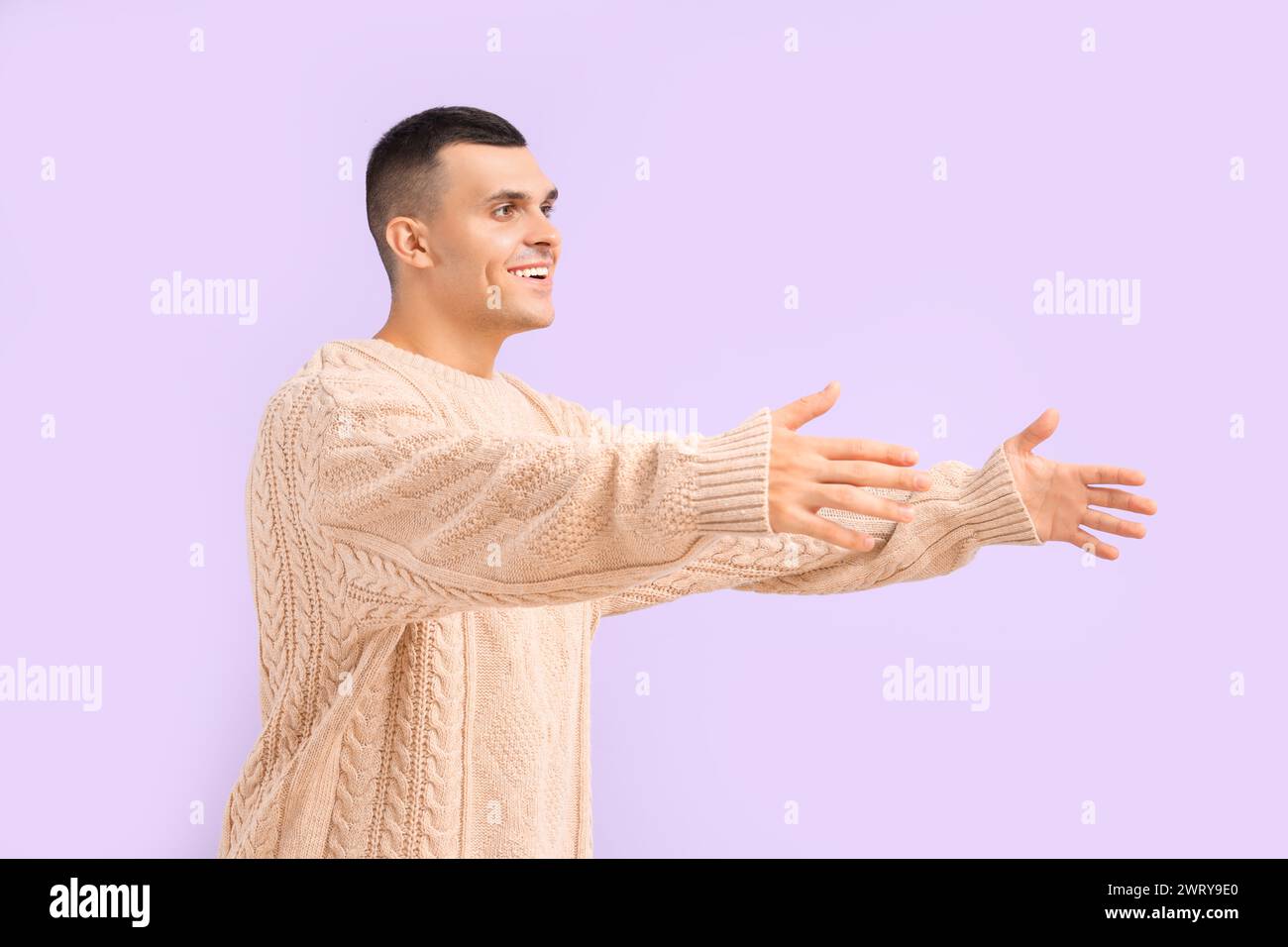 Young man opening arms for hug on lilac background Stock Photo - Alamy