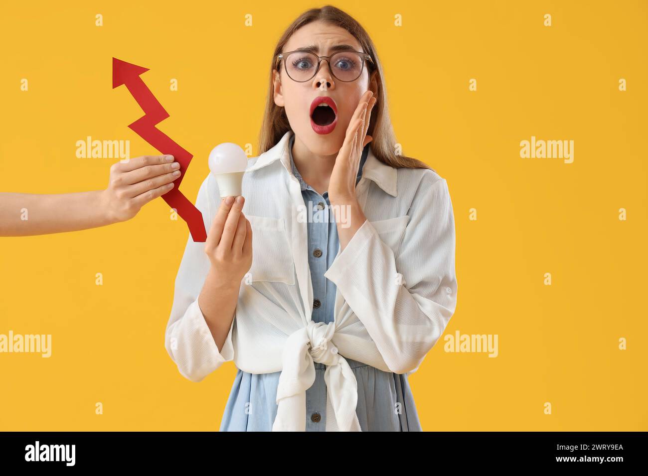 Shocked young woman with light bulb and arrow on yellow background ...