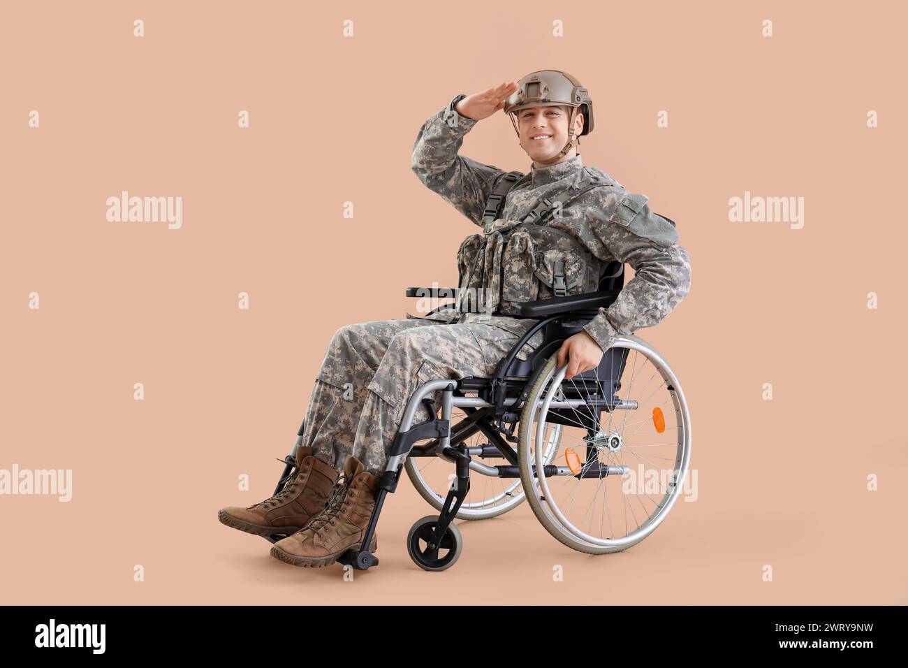 Male soldier in wheelchair saluting on beige background Stock Photo - Alamy