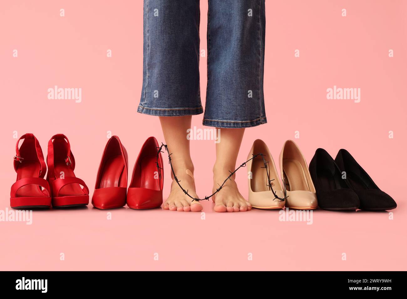Female legs in barbed wire with different shoes on pink background ...