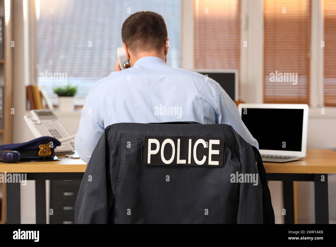 Male police officer working in office, back view Stock Photo - Alamy