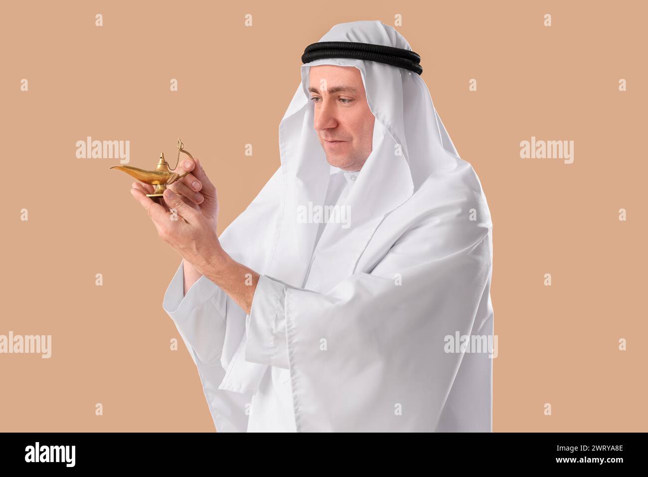 Muslim man with Aladdin lamp of wishes on beige background Stock Photo ...