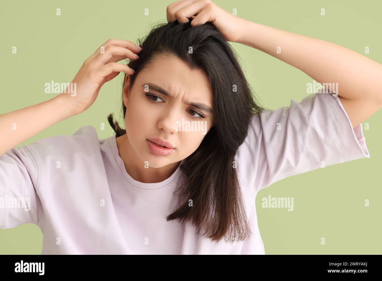 Young woman with dandruff problem examining her hair on green ...