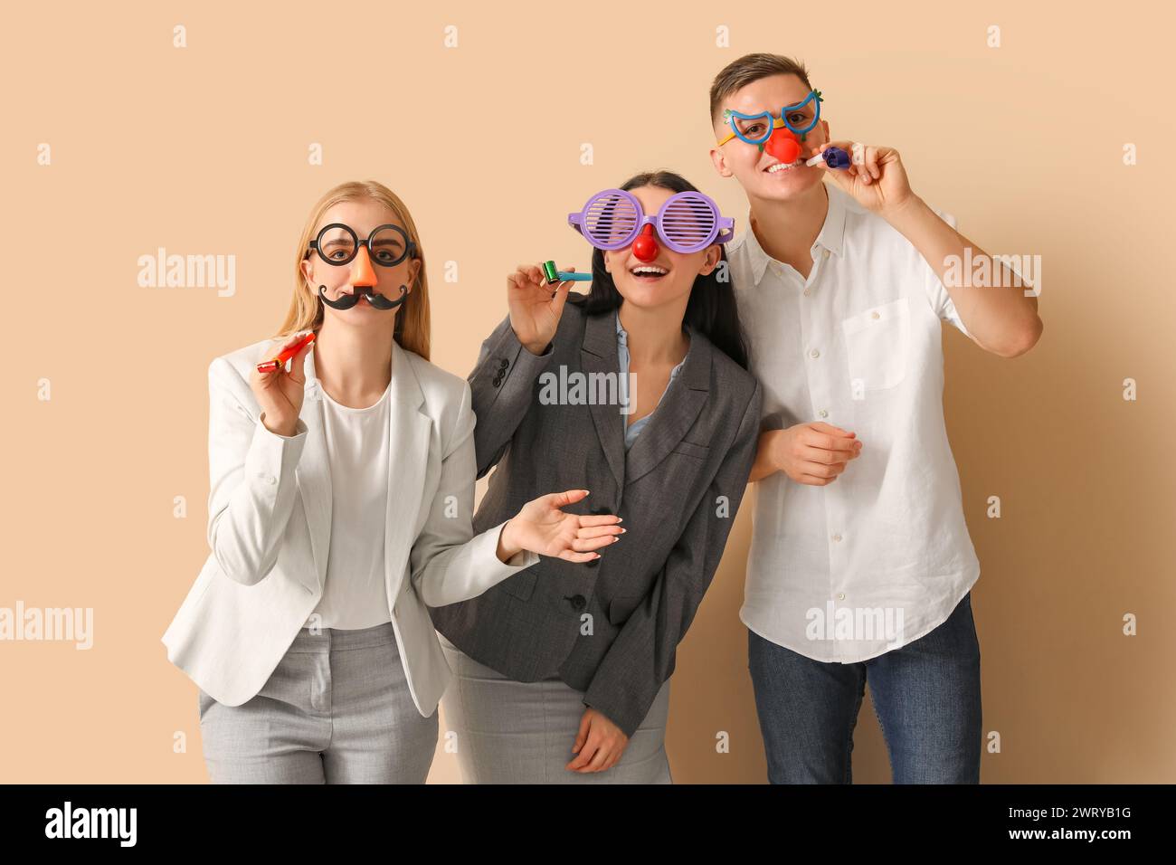 Business people in funny disguise with party whistles on beige ...