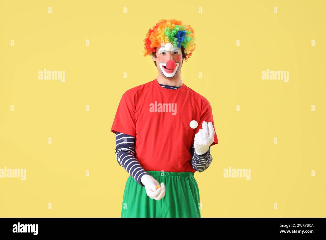 Portrait of juggling clown on yellow background. April Fool's day ...