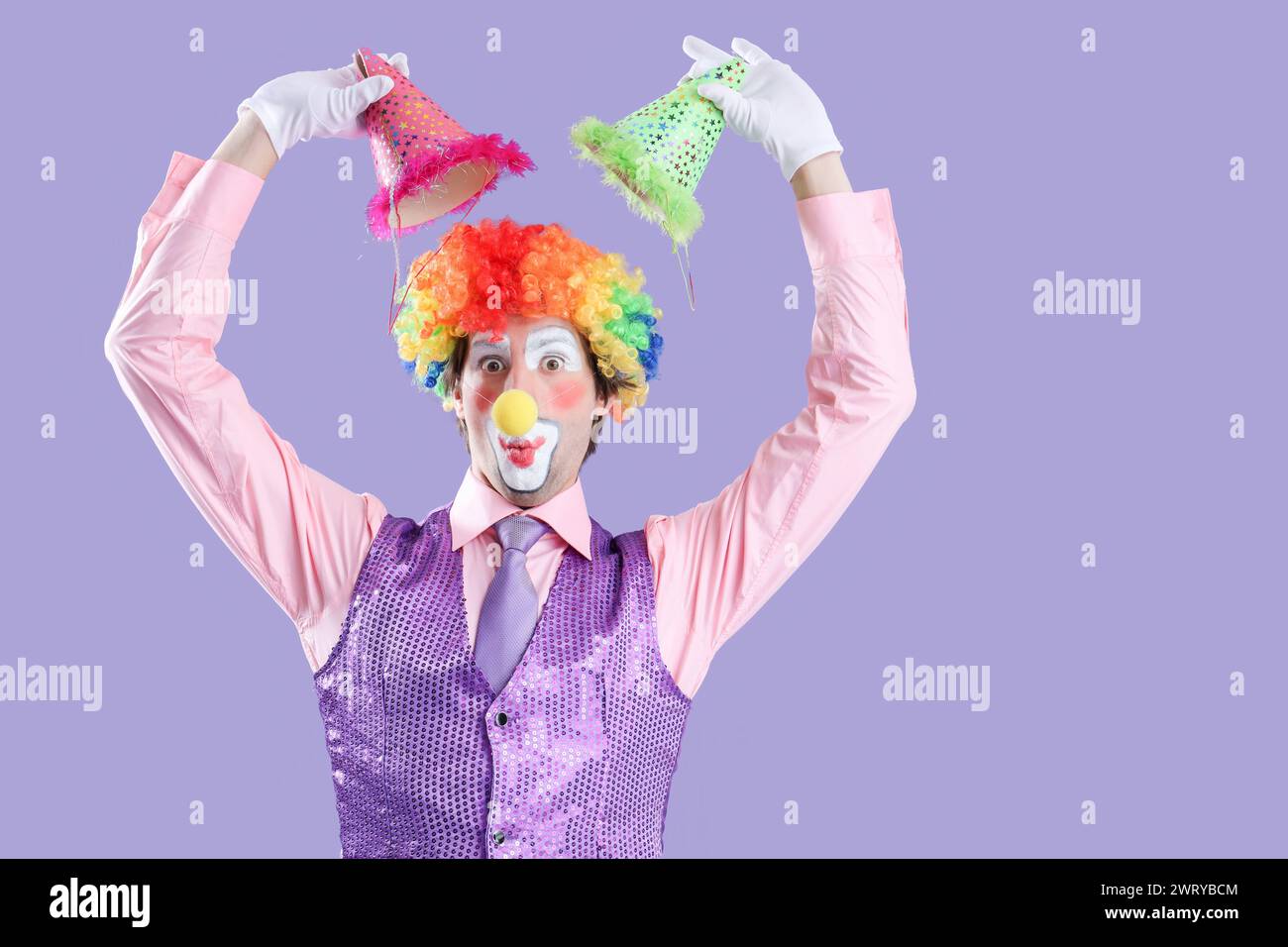 Portrait of clown with party hats on lilac background. April Fool's day ...
