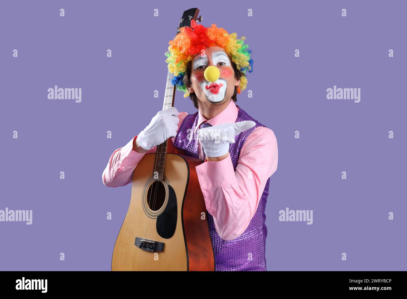 Portrait of clown with guitar blowing kiss on lilac background. April ...