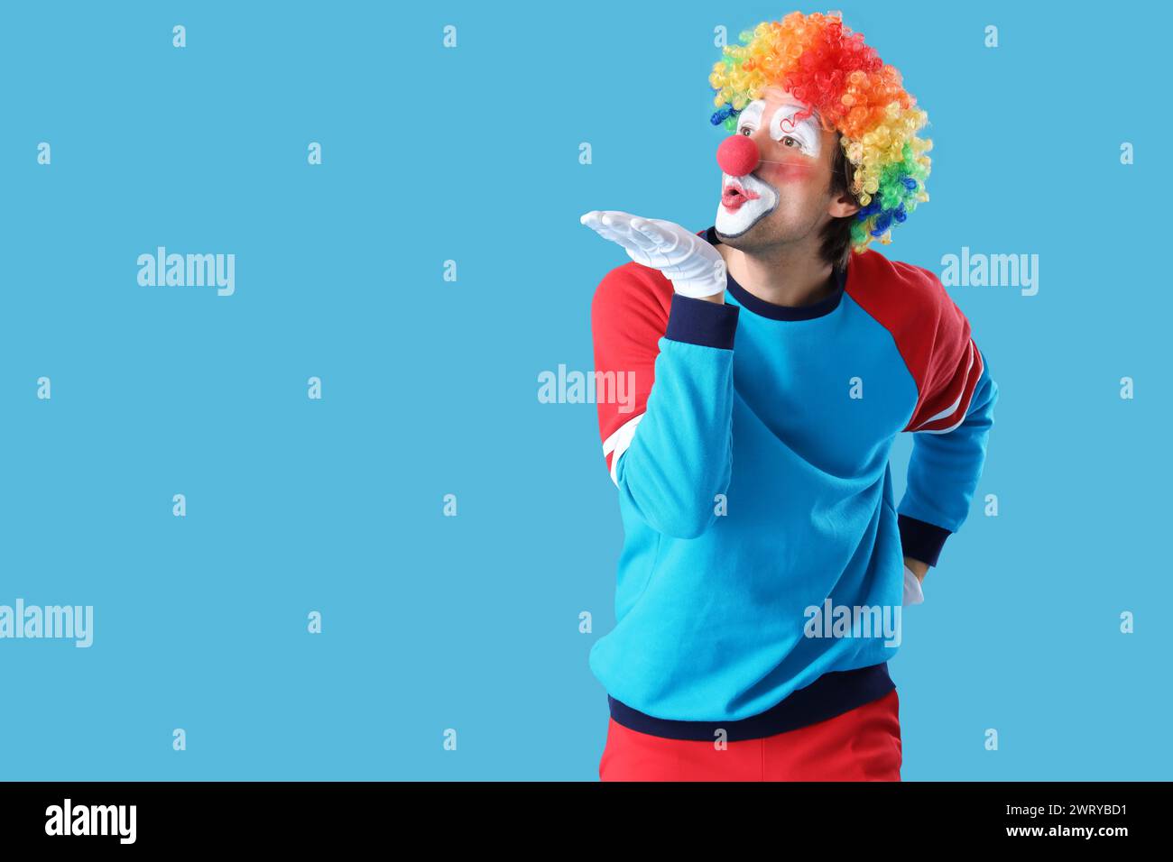 Portrait of clown blowing kiss on blue background. April Fool's day ...