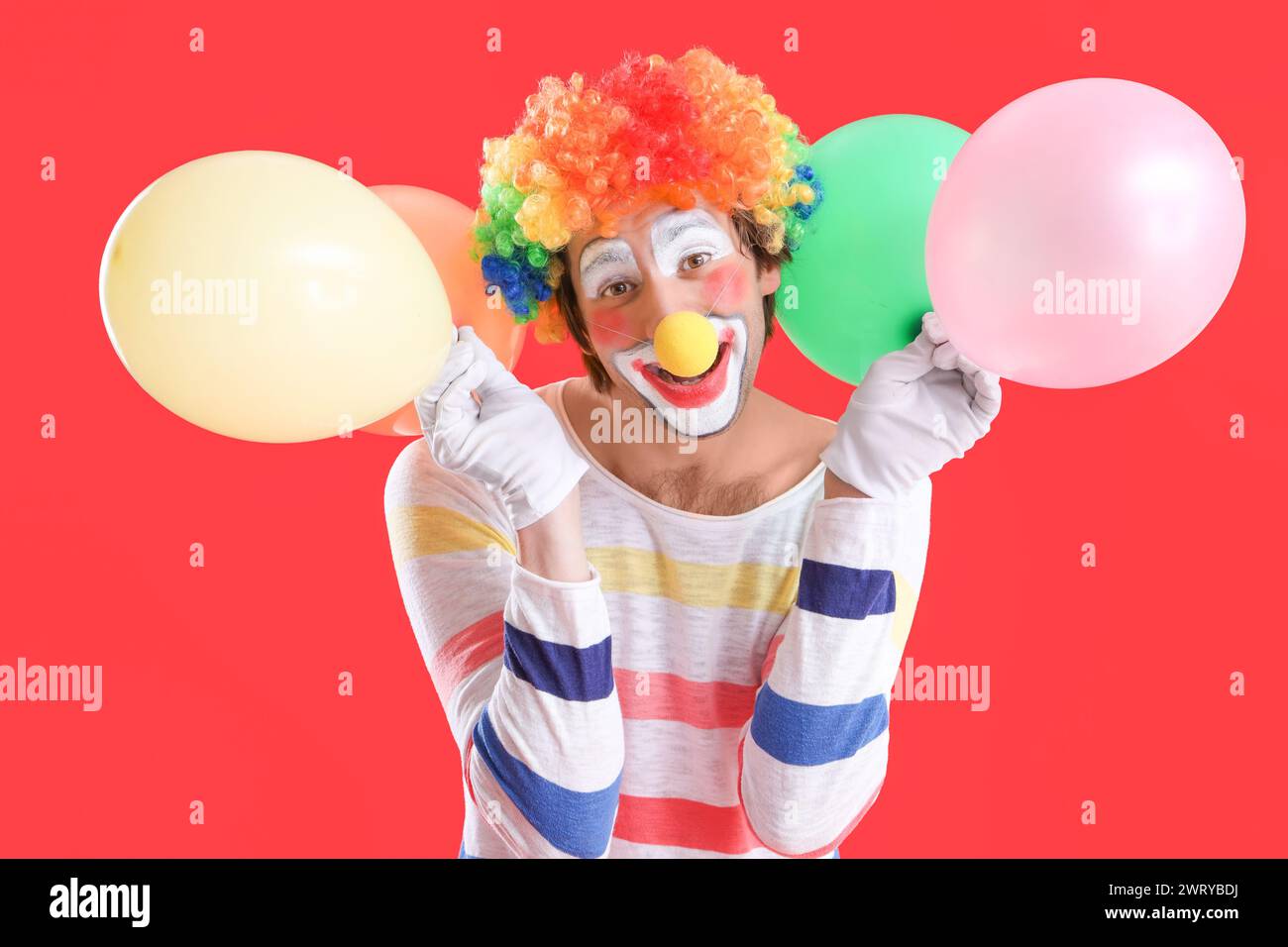 Portrait of clown with balloons on red background. April Fool's day ...