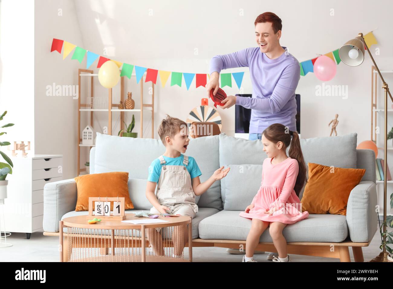 Father surprising his children with whoopee cushion at home. April Fool ...