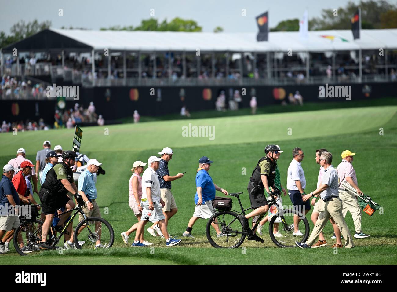 Police officers and spectators make their way across the 18th fairway ...