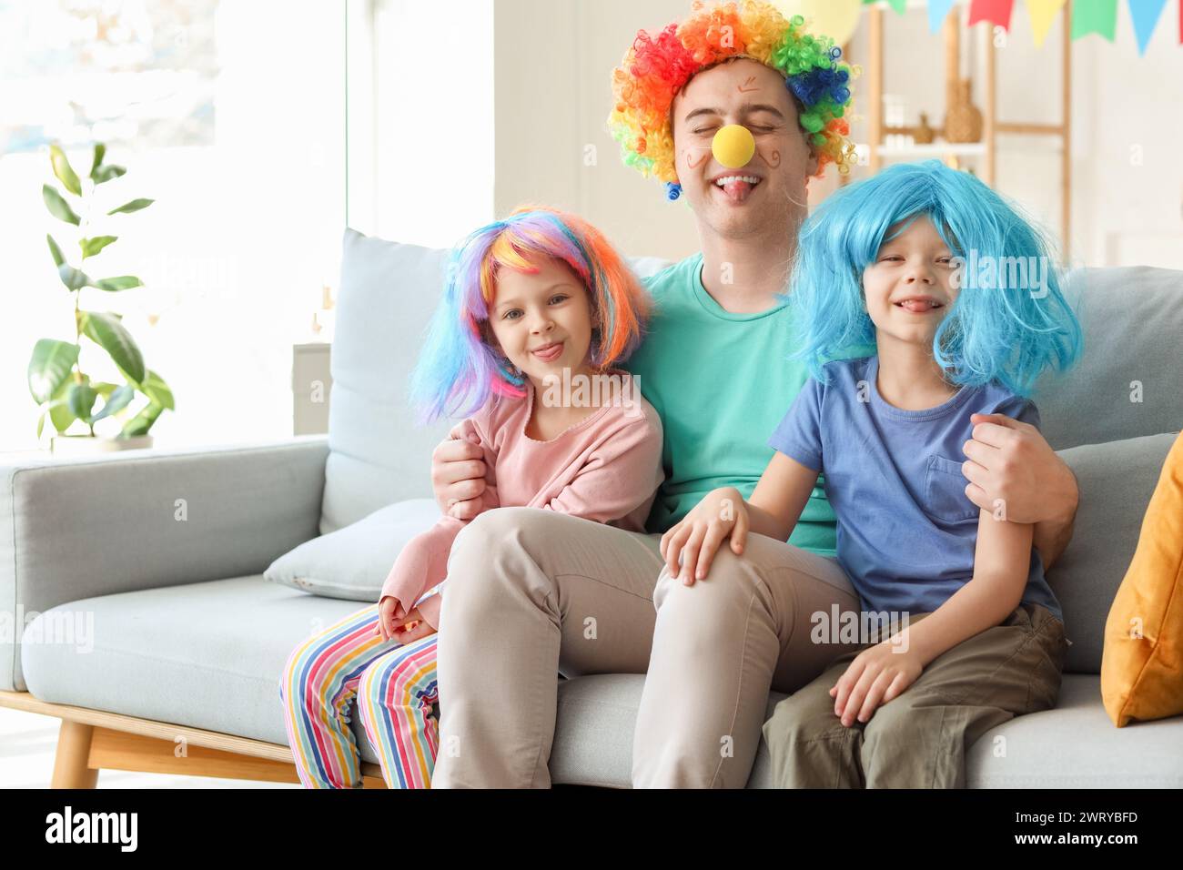 Father and his children with colorful wigs at home. April Fool's Day ...