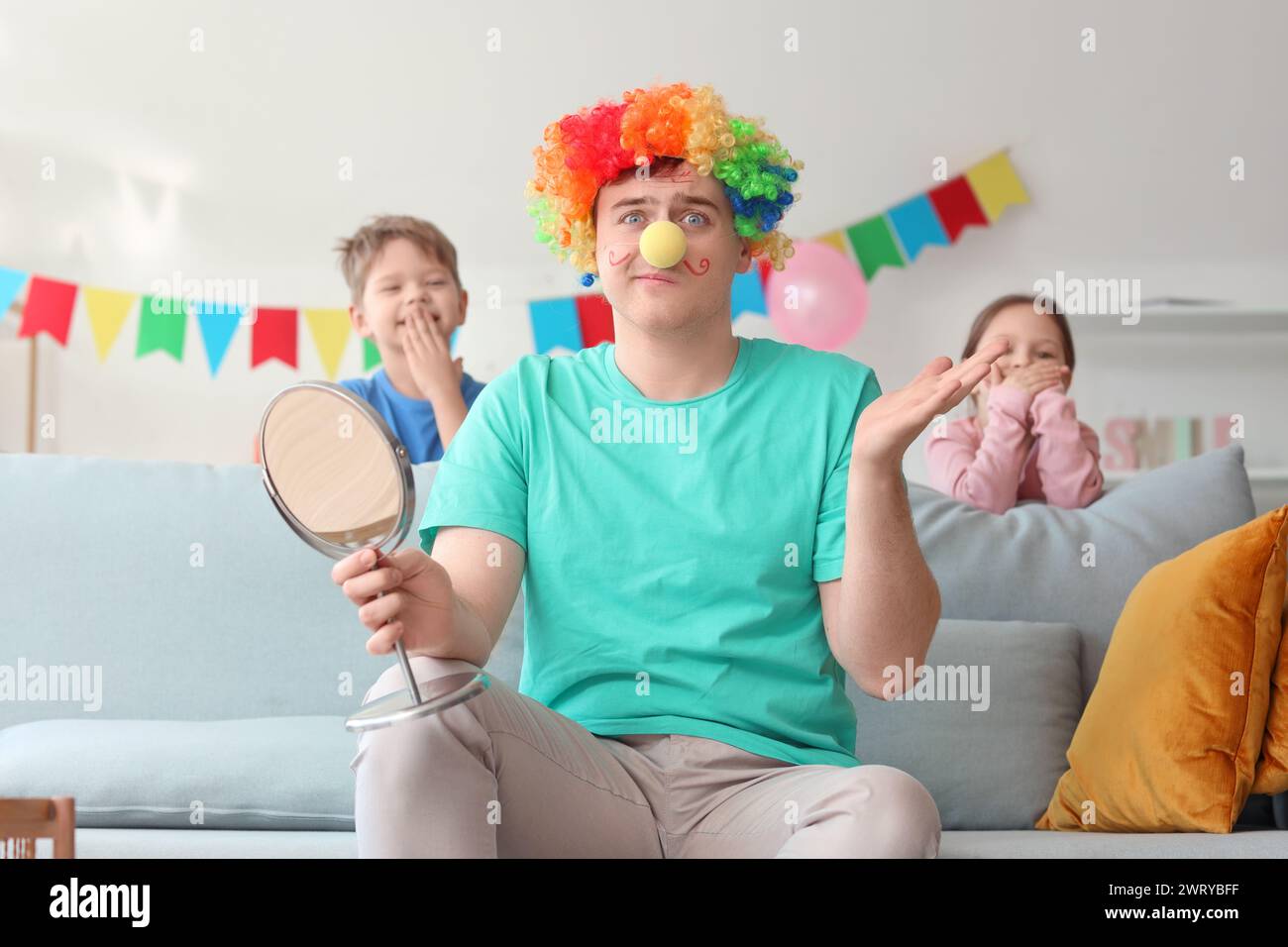 Little kids laughing at their father with colorful clown wig and ...