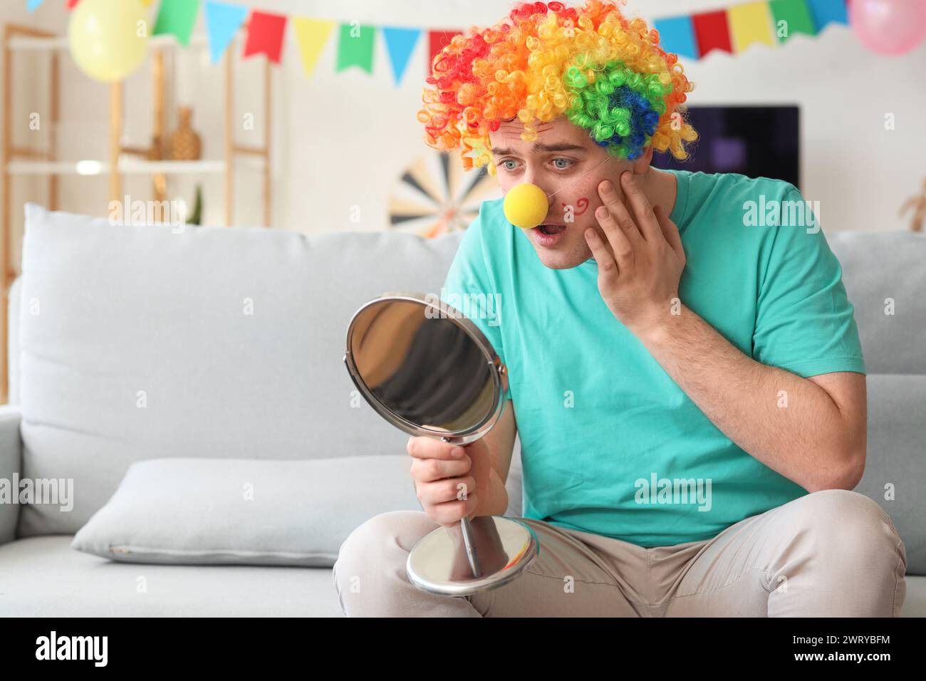 Shocked young man with colorful clown wig and paintings on his face ...