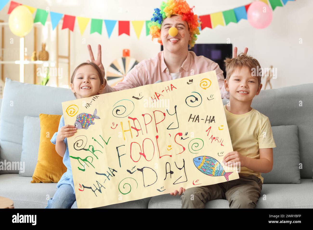 Father in colorful clown and his children with April Fool's Day poster ...