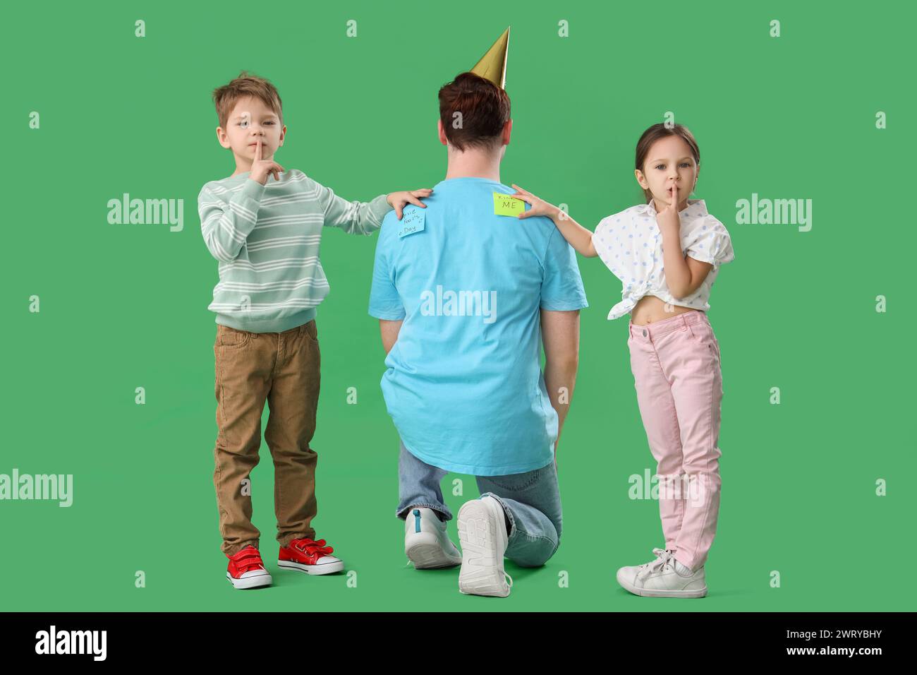 Little kids sticking paper stickers to their father's back on green ...