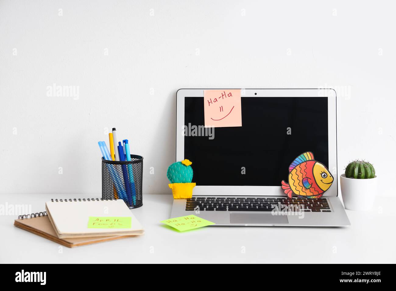 Workspace with laptop, funny sticky notes and paper fish on white ...