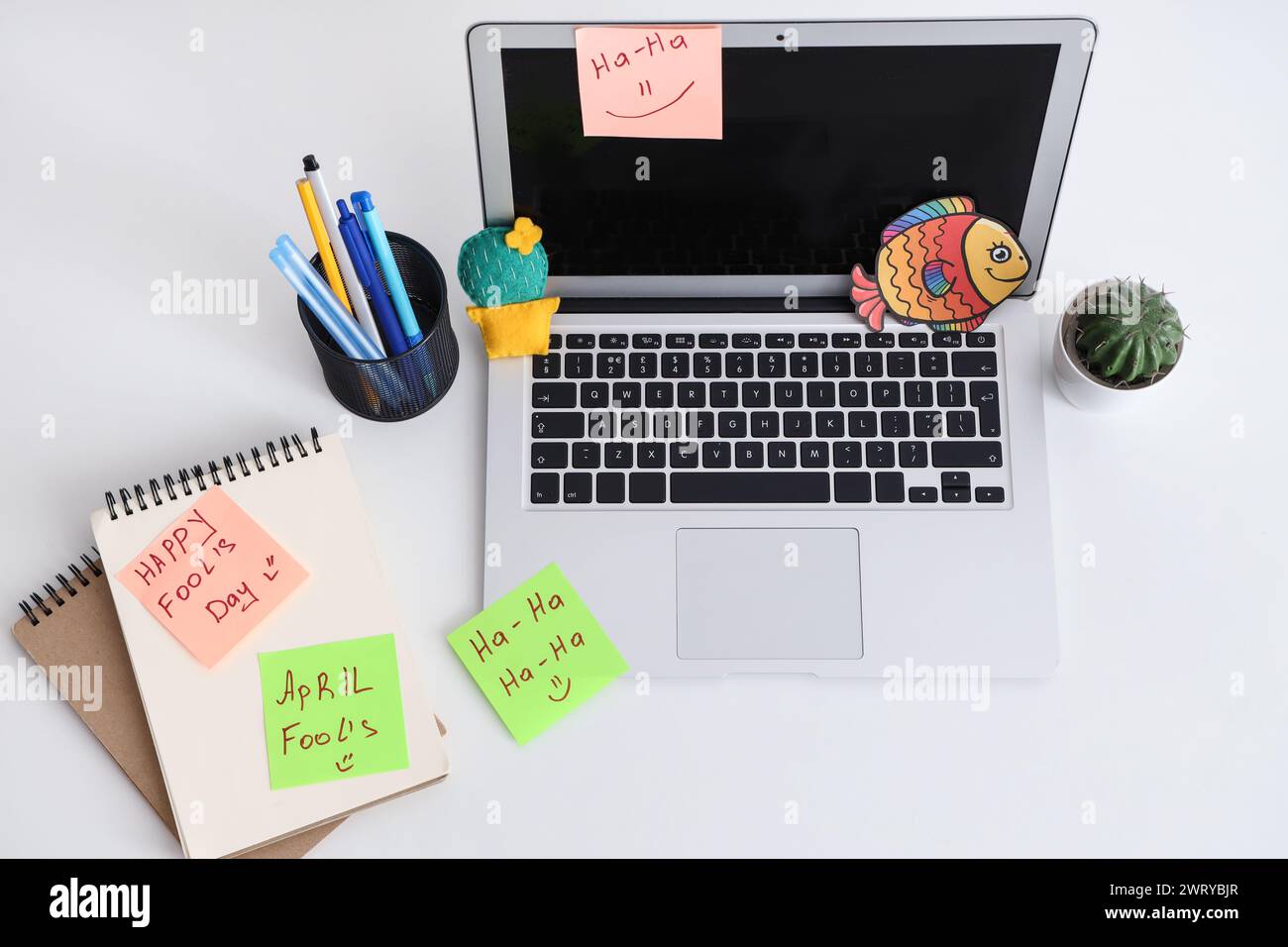 Workspace with laptop, funny sticky notes and paper fish on white ...