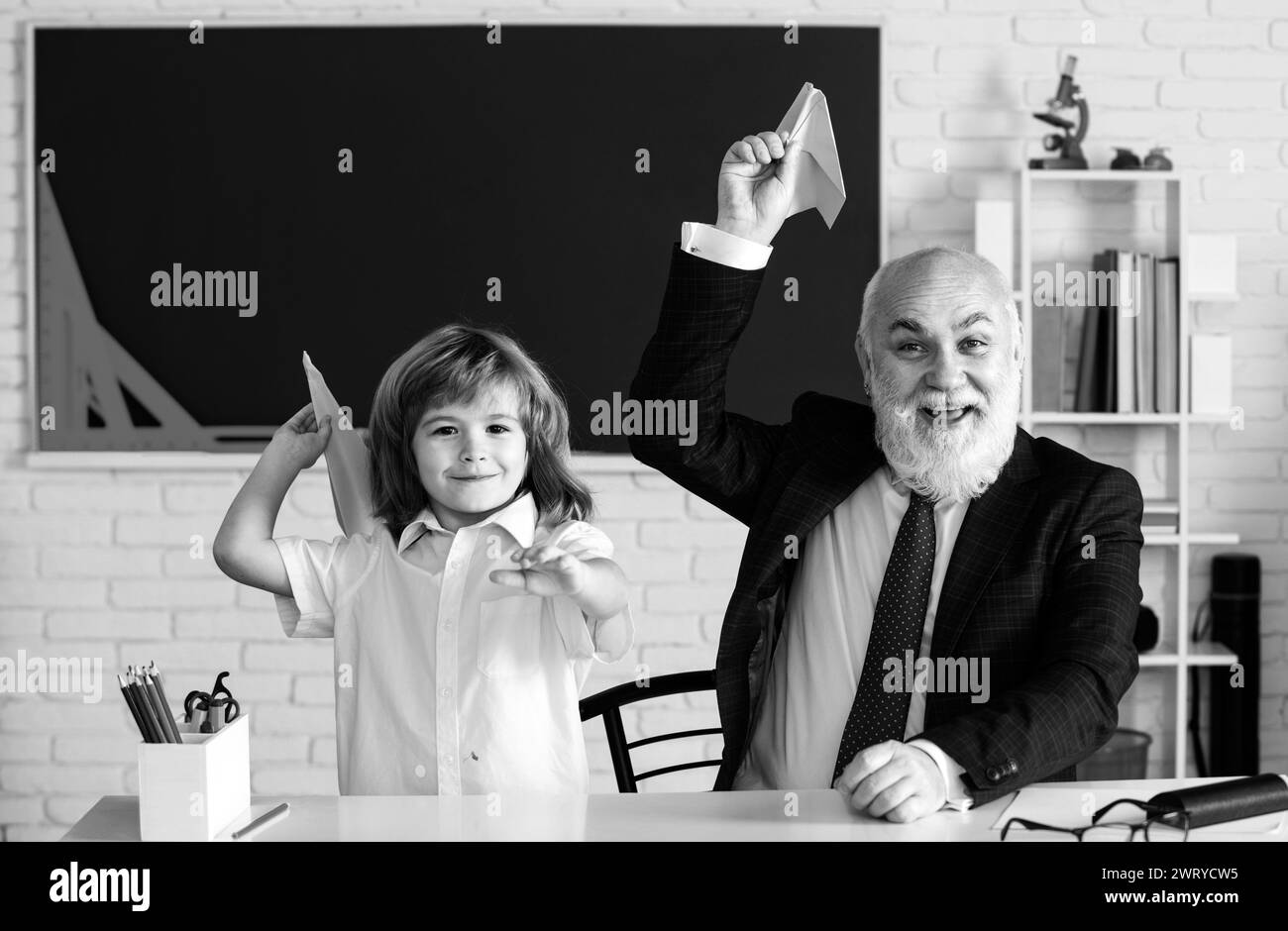 Teacher and school boy with paper airplane. Pedagogue and pupil having ...