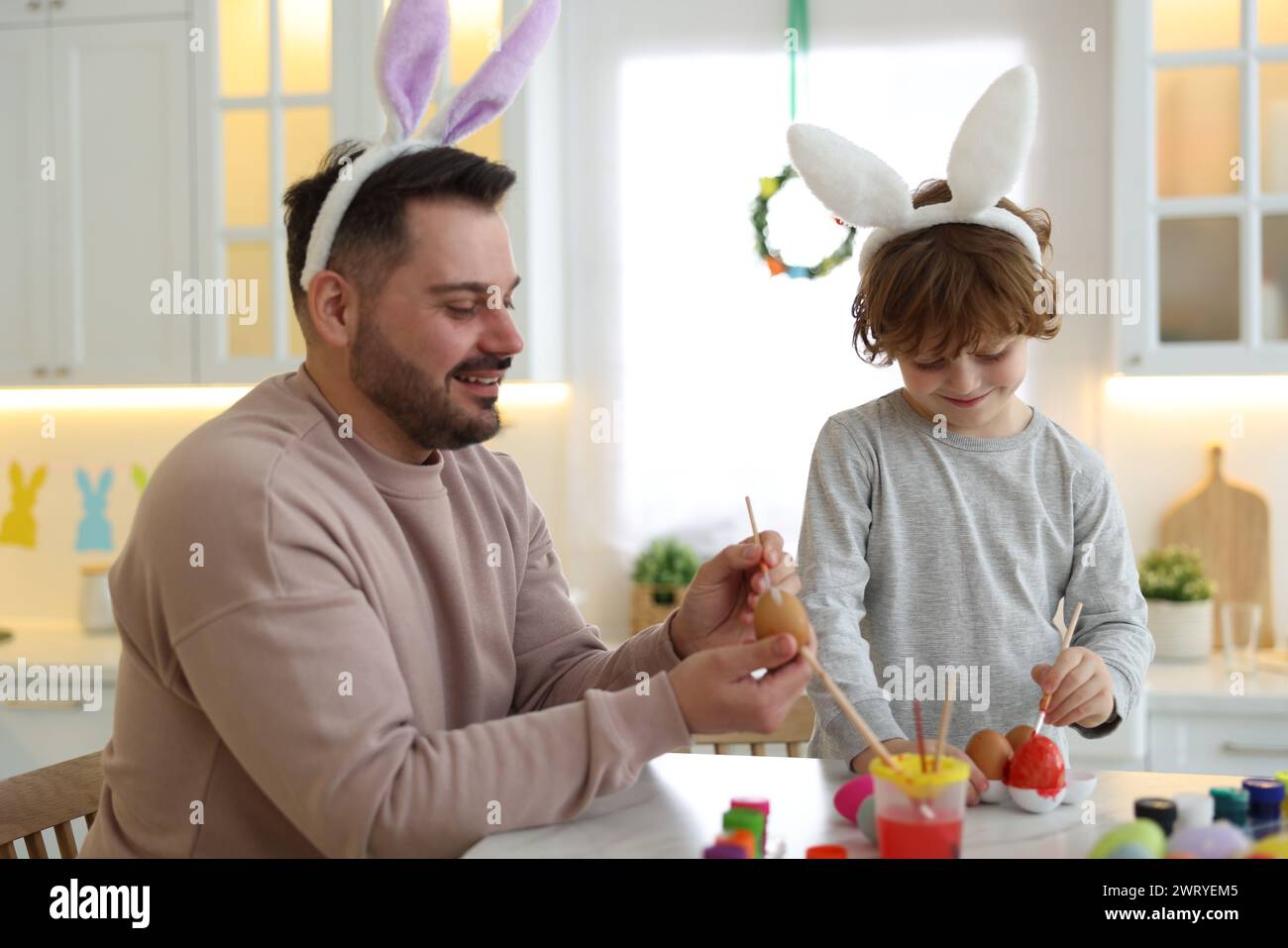 Easter celebration. Father with his little son painting eggs at white ...