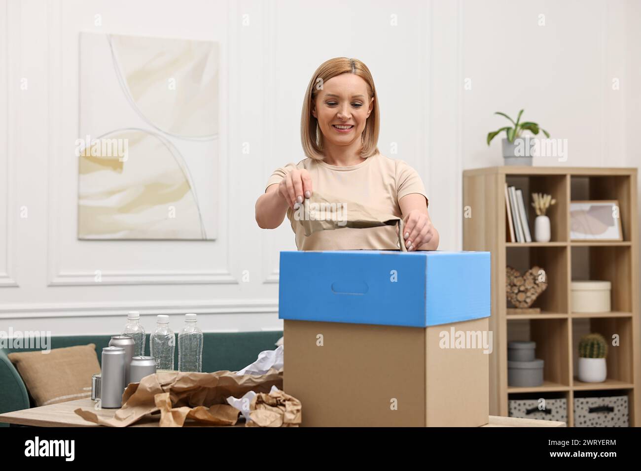 Garbage sorting. Smiling woman throwing crumpled paper into cardboard ...