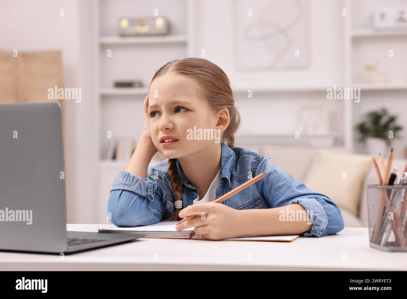 Little girl suffering from headache while doing homework at home Stock ...