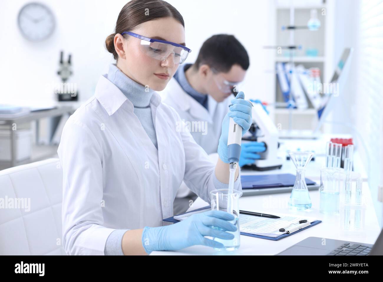 Scientist dripping sample into beaker in laboratory Stock Photo - Alamy