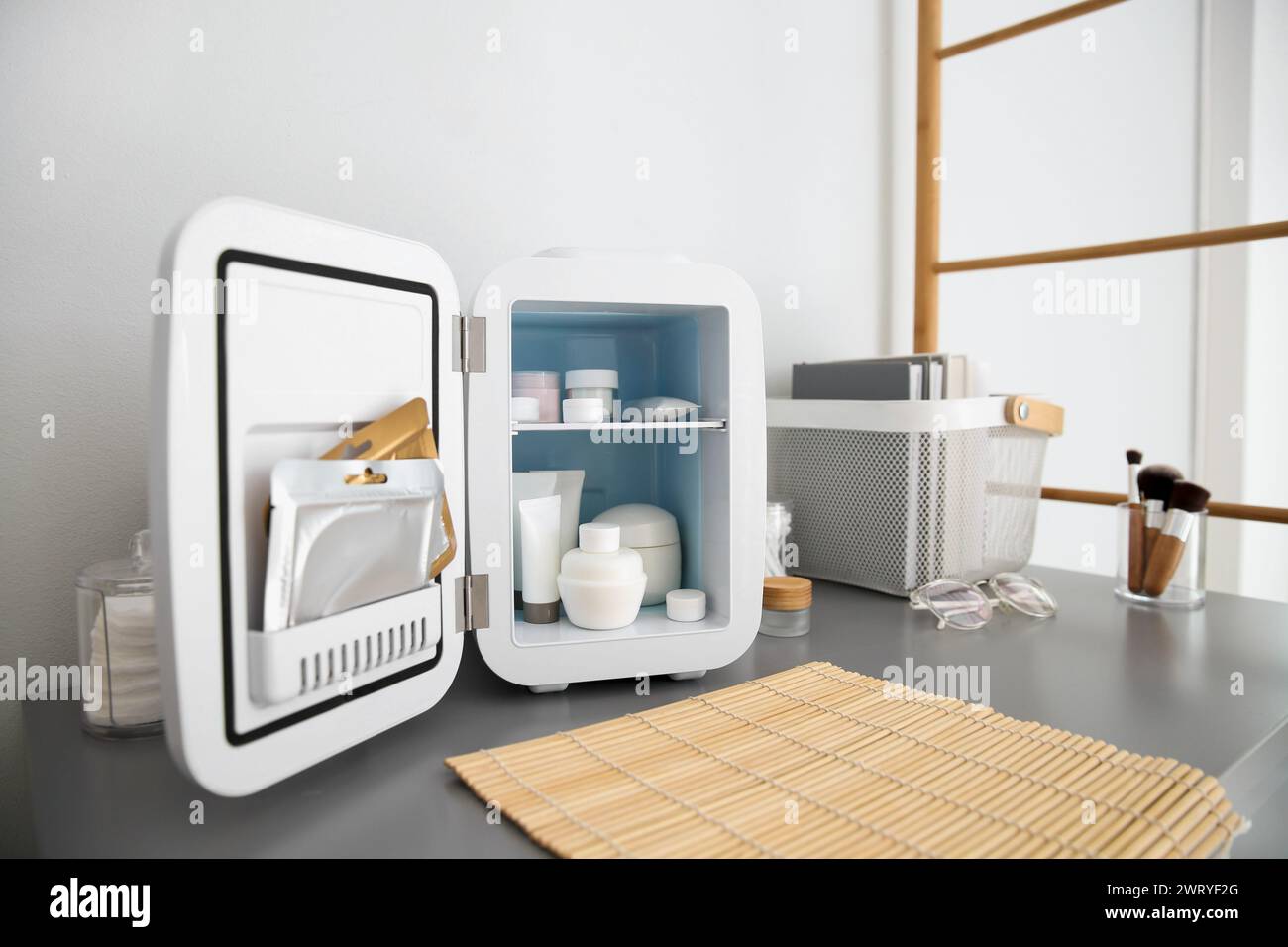 Mini fridge with cosmetic products on grey vanity table indoors Stock ...