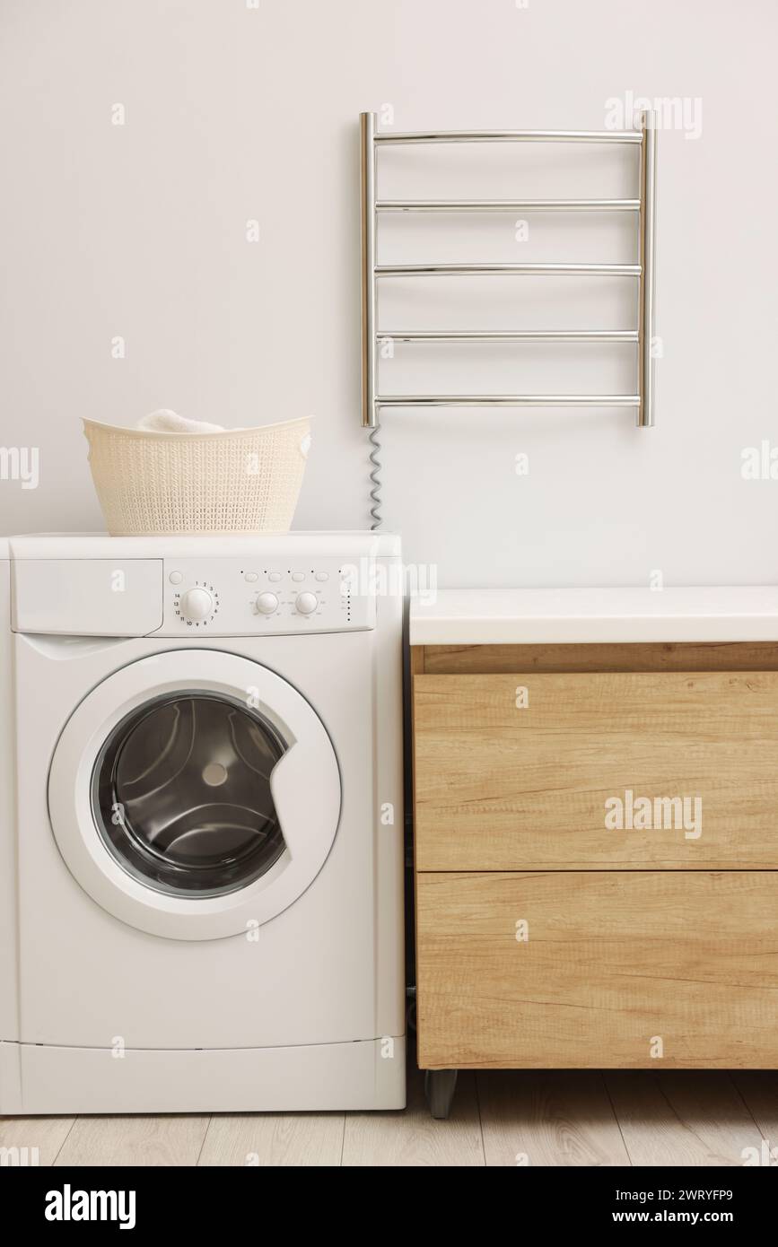 Stylish bathroom interior with heated towel rail and washing machine ...