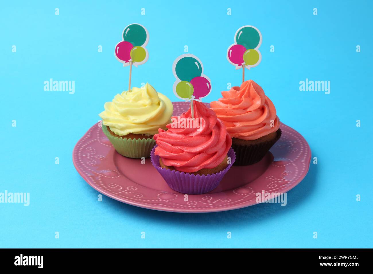 Delicious cupcakes with bright cream and toppers on light blue ...
