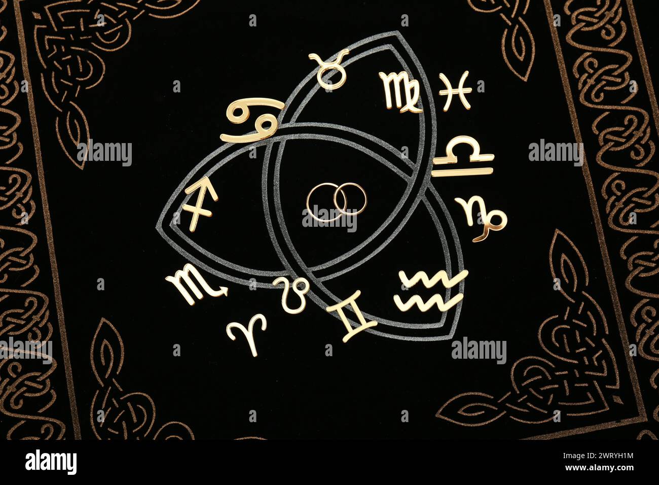 Zodiac signs and wedding rings on book, flat lay Stock Photo - Alamy