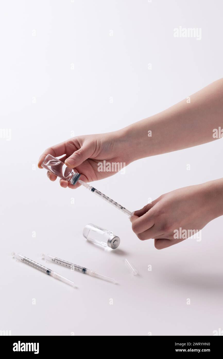 putting a syringe in an injection bottle Stock Photo - Alamy