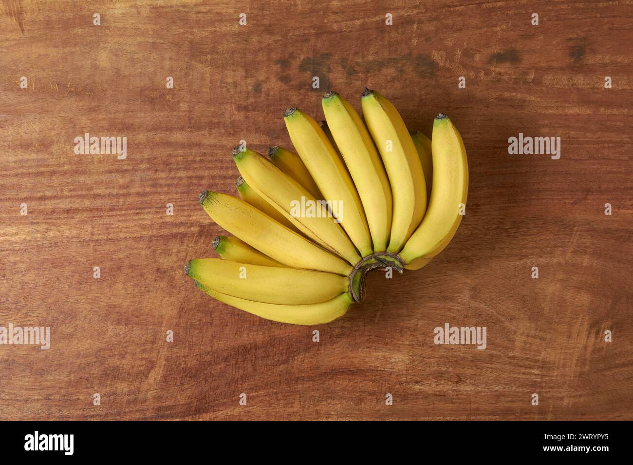 bunch of fresh bananas on a wooden table top, harvested ripe tropical ...