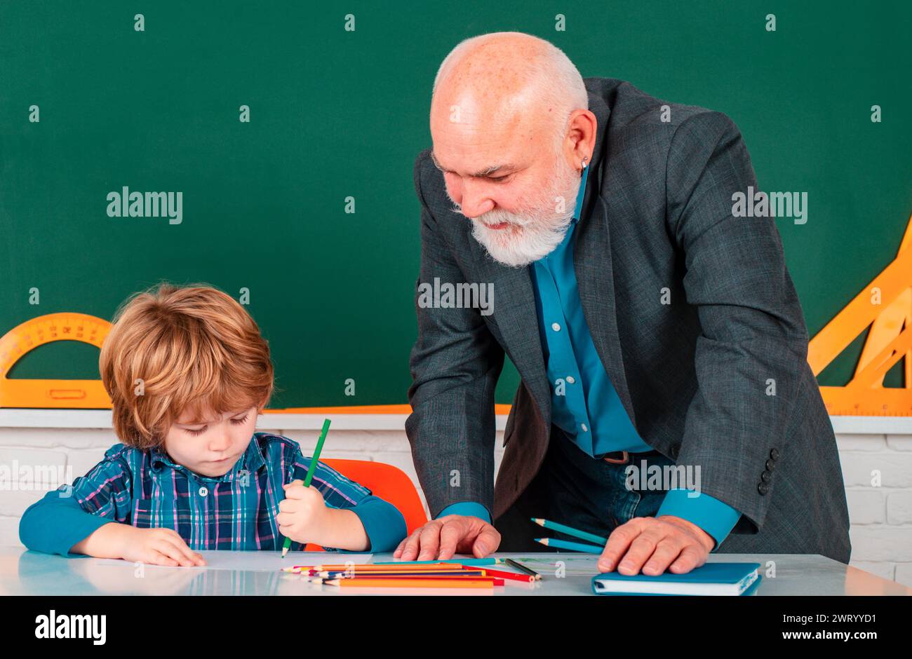 Senior teacher with pupil at back of classroom at the elementary school ...
